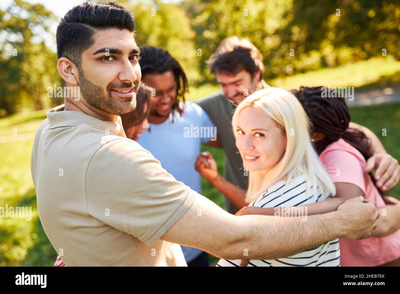 Young people embrace as a community in a circle in the team building ...