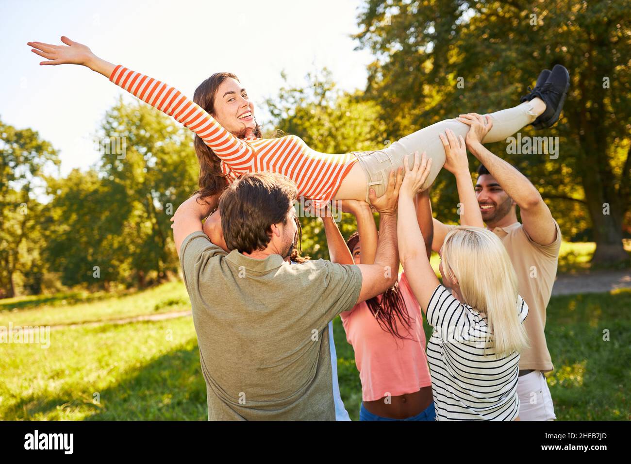 Young people lift up a woman together as an exercise in trust and ...