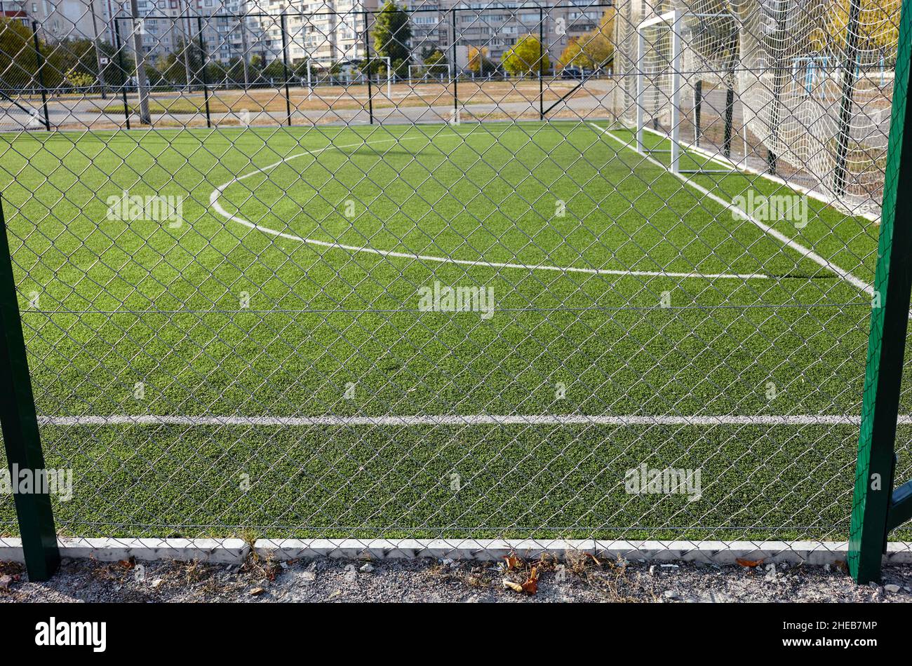 Lawn field for playing football behind the green fence mesh. Close-up ...
