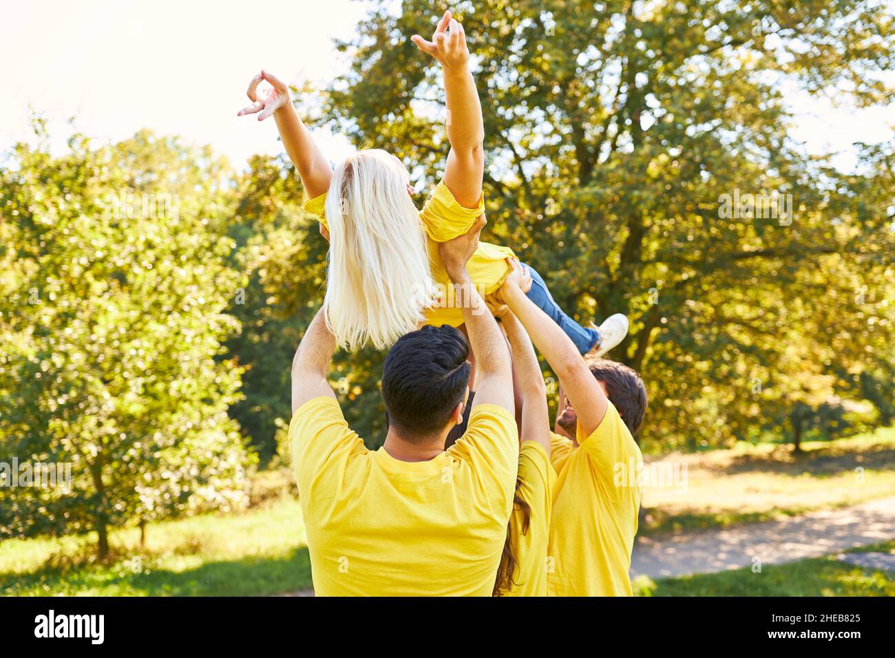 Group of people during a trust and team building exercise lifts one ...