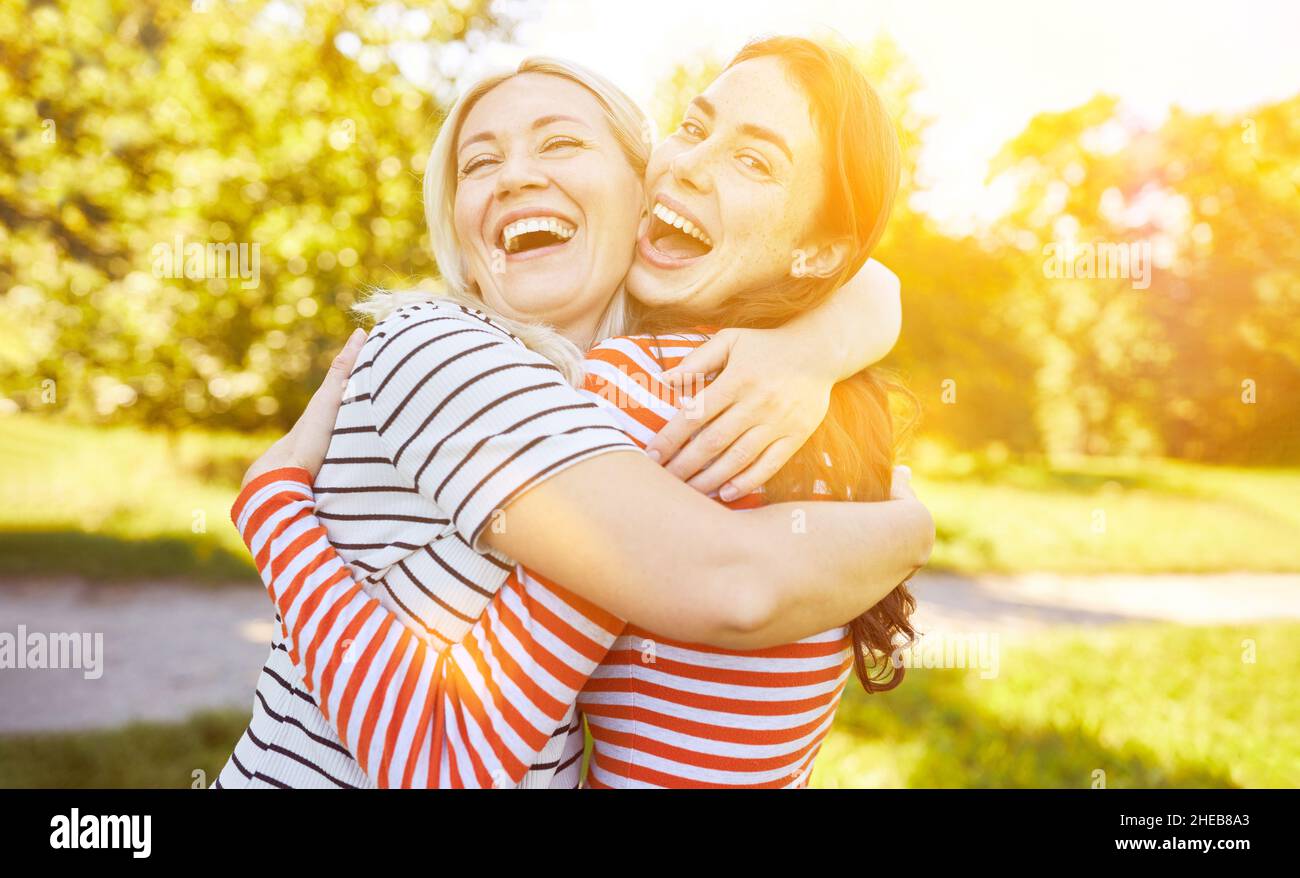 Two Happy Young Women Laughing Hug Each Other In The Park In Summer