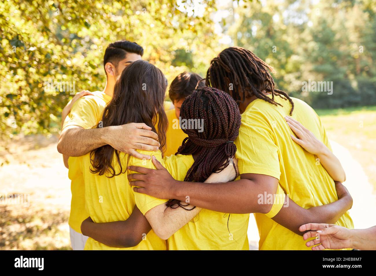 Group of people at team building exercise put heads together and hug in nature Stock Photo - Alamy