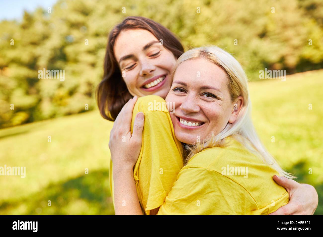 Two young friends happily hug each other when they meet again in nature ...