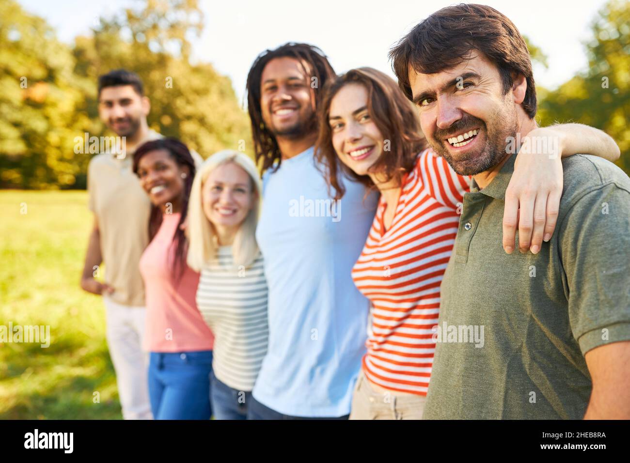 Diverse happy group of friends hugging in nature in summer Stock Photo ...