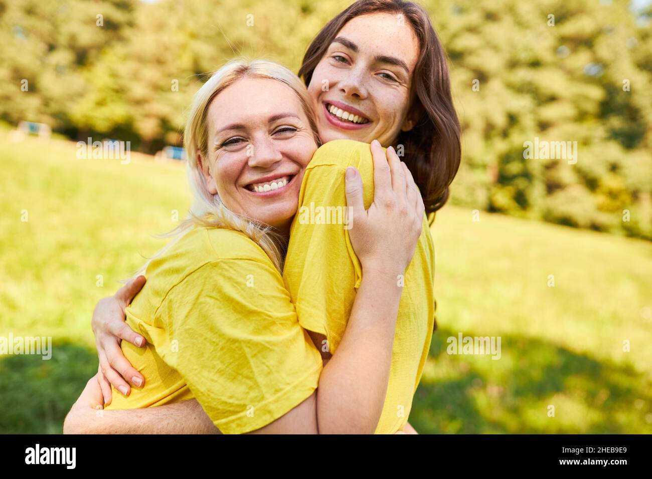 Two young women as best friends hug each other happily in the park in ...