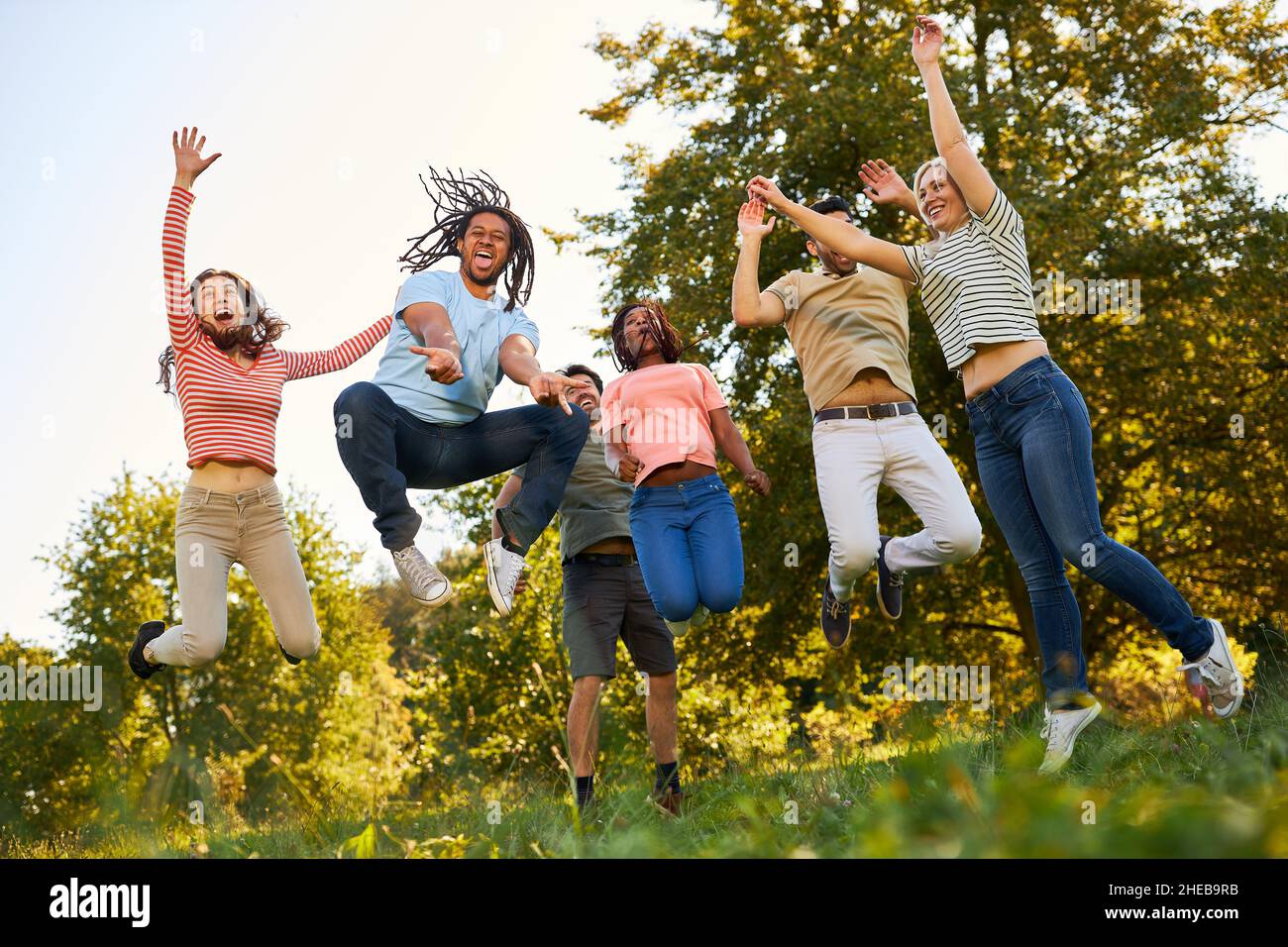 Young people have fun together and jump and hop on a meadow in summer ...