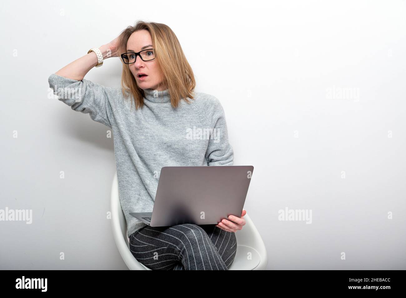 surprised blond woman with eyeglasses working on computer, remote work ...