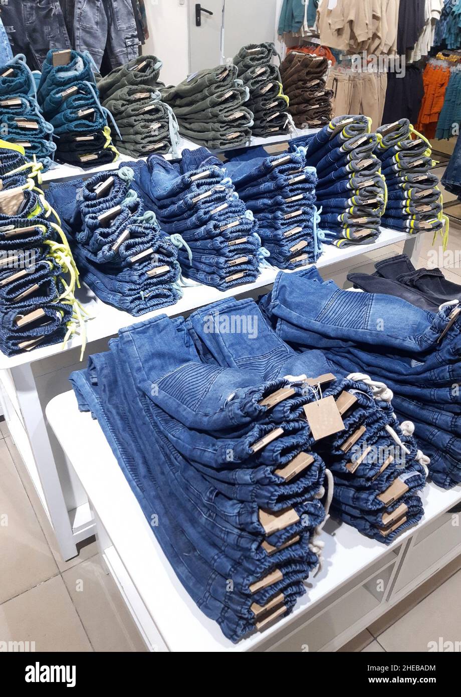 Straight rows of denim trousers of different shades lie on the shelves ...