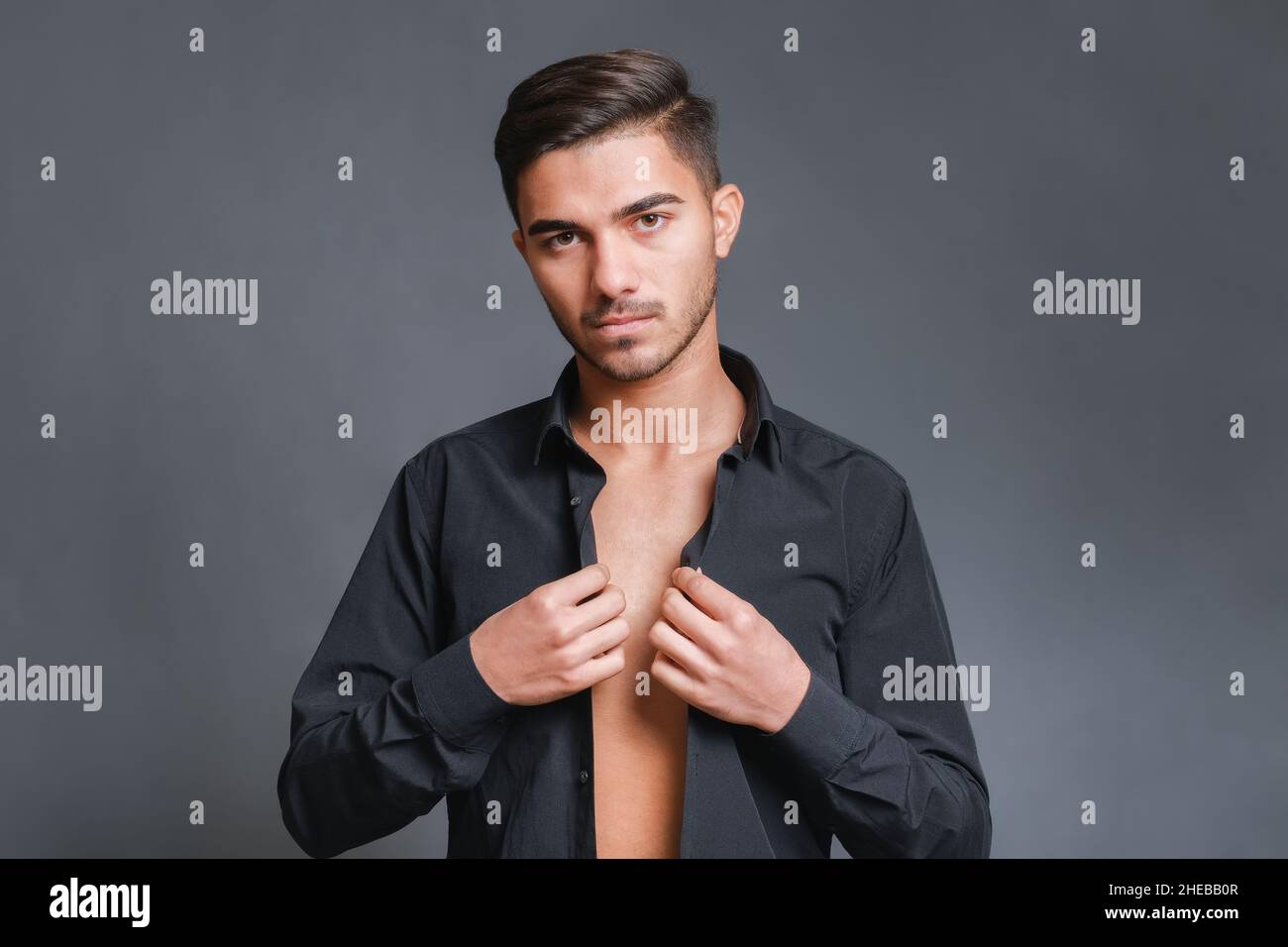 Portrait of unshaven young man buttoning up black shirt Stock Photo - Alamy