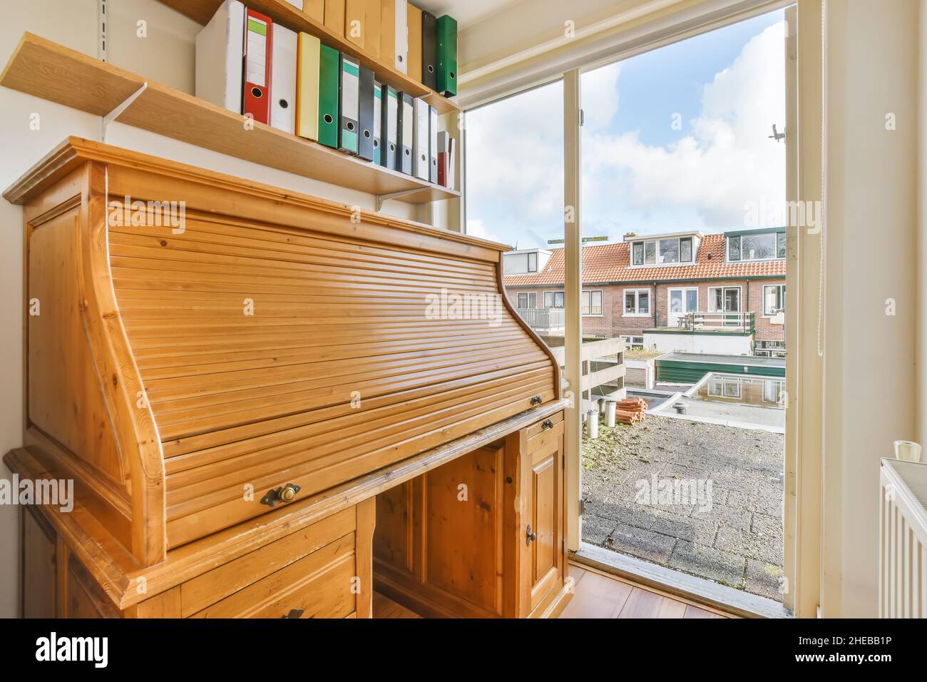 A closed table with shelves full of folders above it and an open door ...