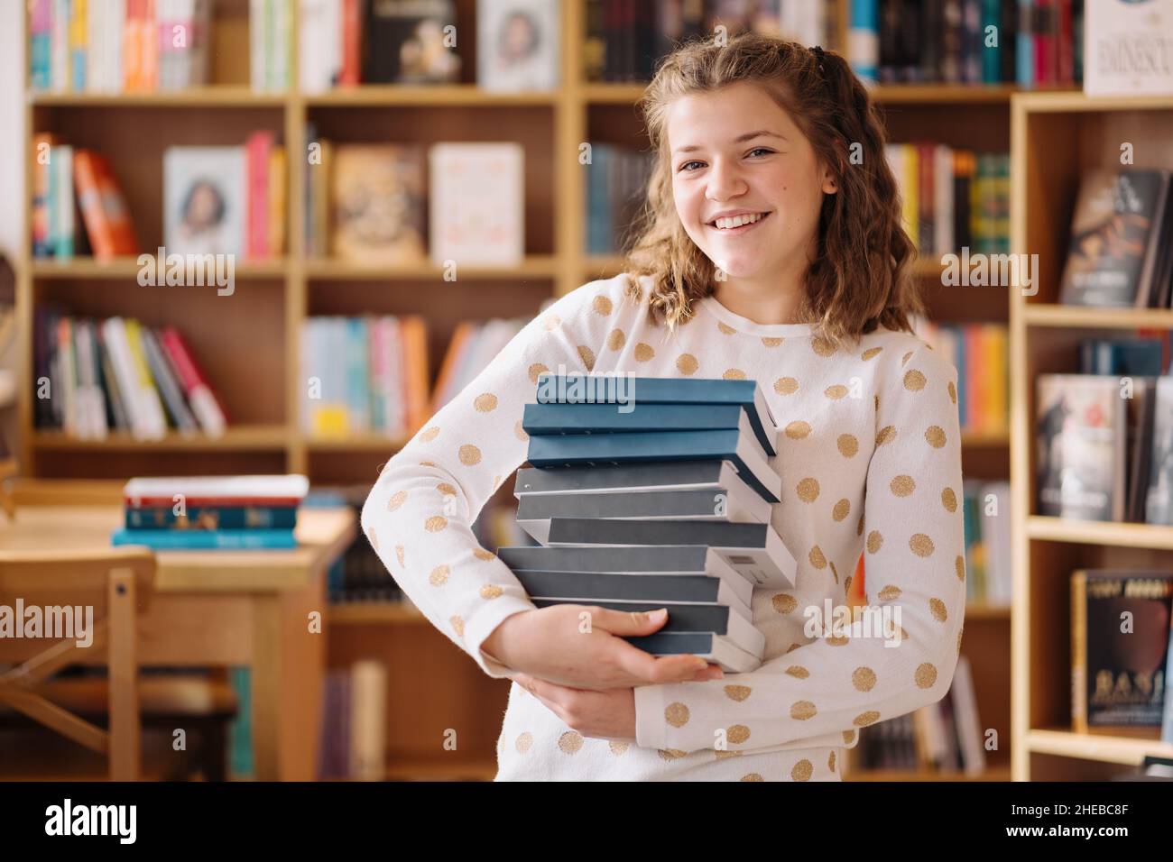 Teen girl among a pile of books. A young girl holding books with ...