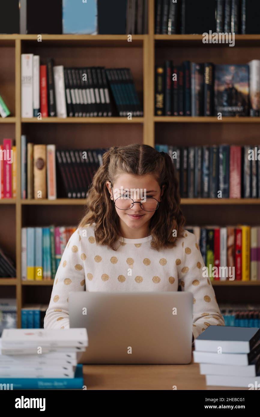 Attractive happy young girl student studying at the college library ...