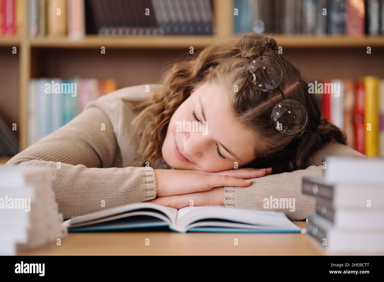 Young women got asleep on the books while studying, reading glasses on ...