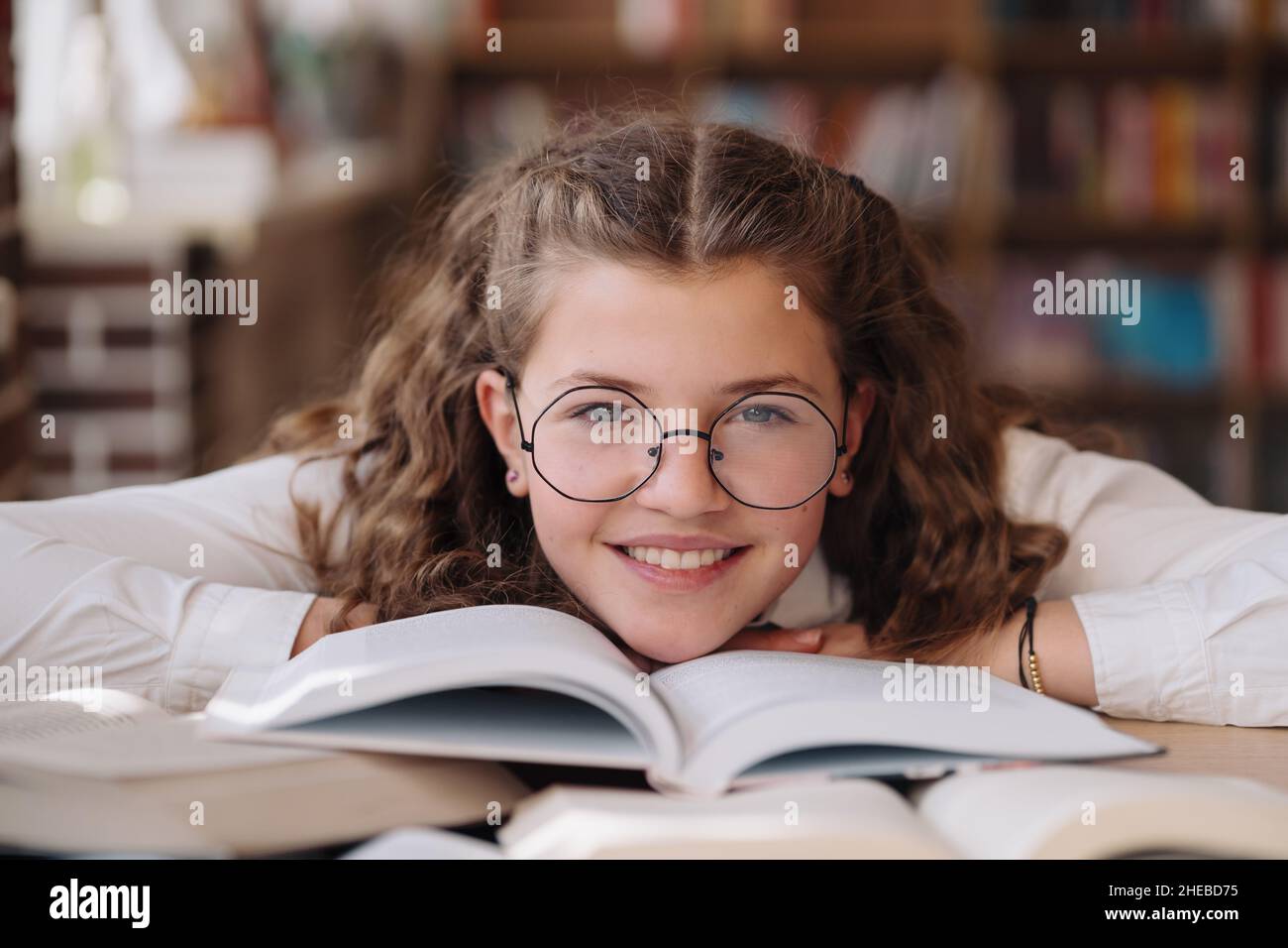 Attractive happy young girl student studying at the college library ...