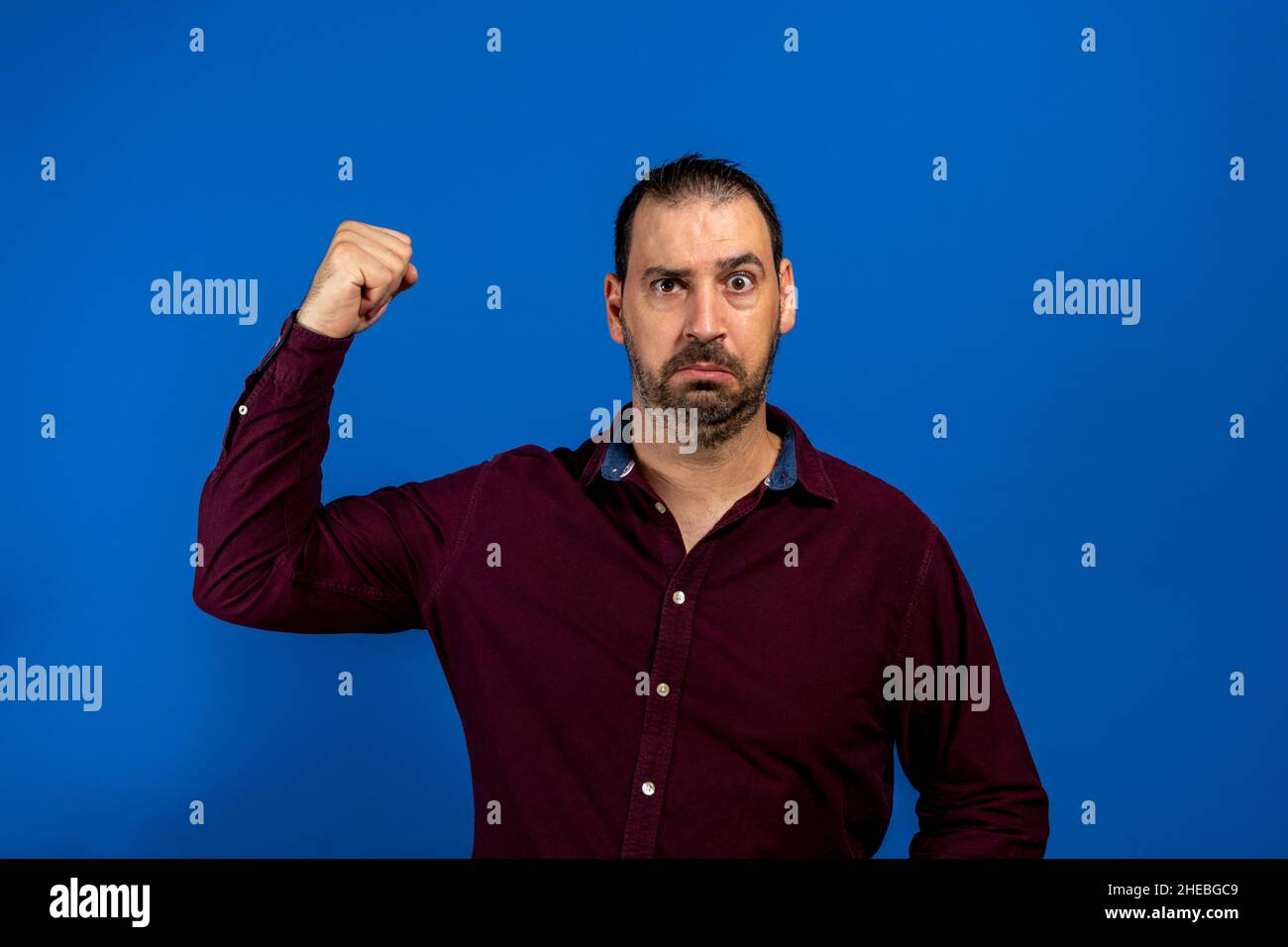 Spanish bearded man in a purple shirt pulling out muscle with a puzzled ...