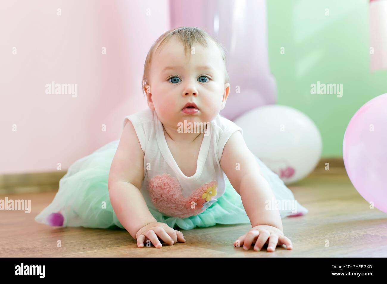 A cute one-year-old girl in a beautiful dress looks at the camera Stock ...