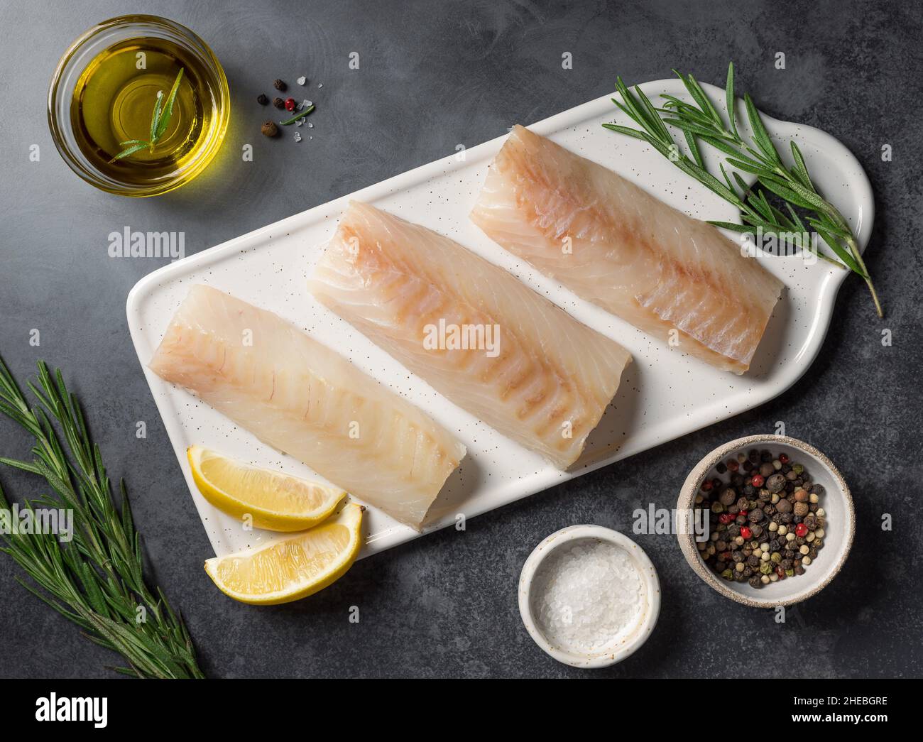 Raw cod fillet with lemon, rosemary and spices Stock Photo - Alamy