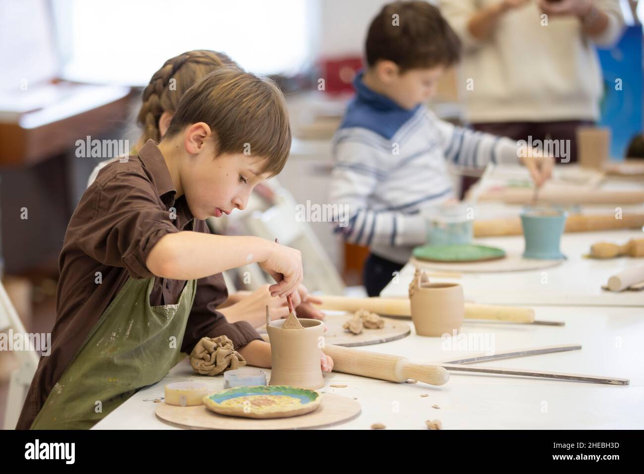 Creative workshop. A little boy makes a cup in a clay modeling lesson ...