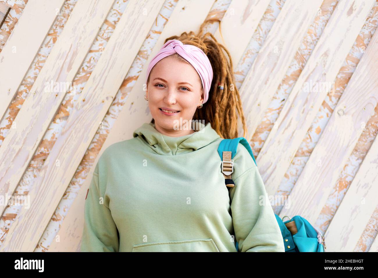 Beautiful young smiling woman with dreadlocks poses against a pink ...
