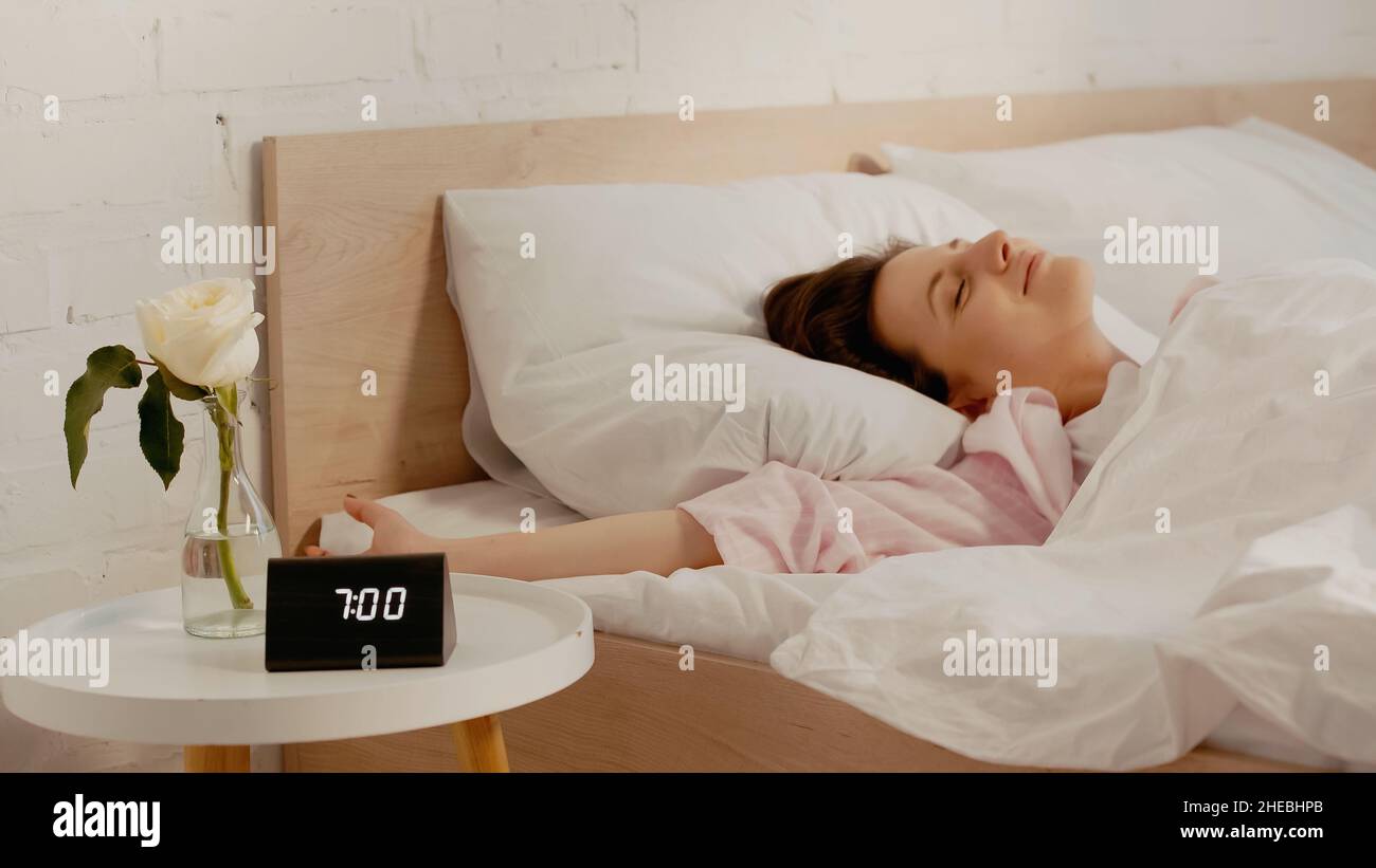 Young brunette woman lying n bed near clock on bedside table Stock Photo - Alamy