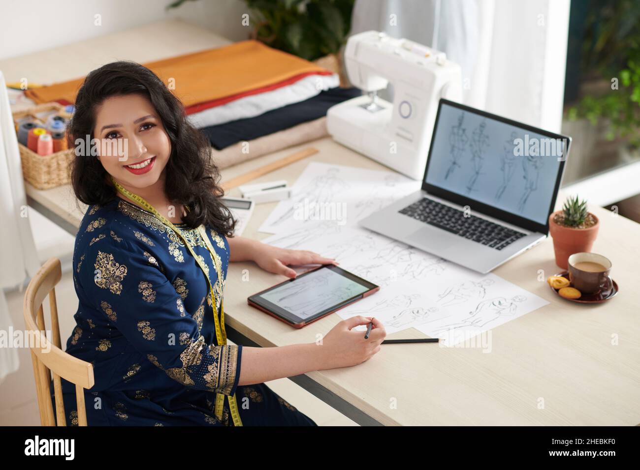 Happy seamstress drawing fashion sketches for customers Stock Photo - Alamy