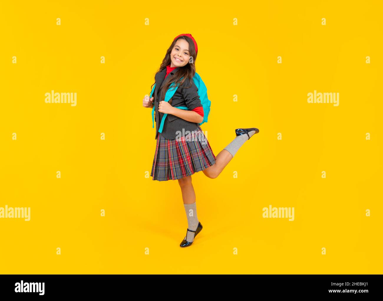 happy kid in school uniform and backpack jump on yellow background ...