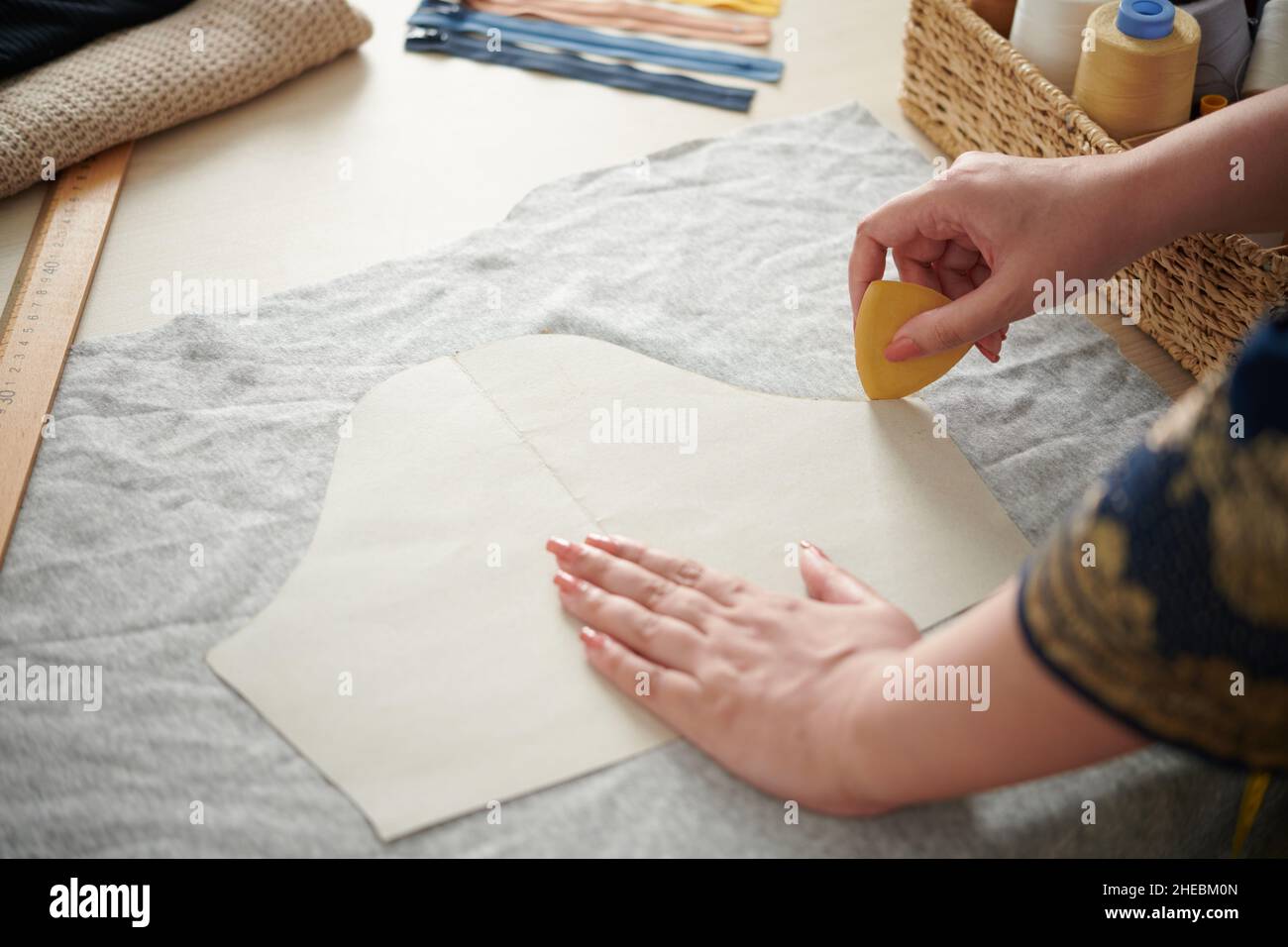 Closeup image of tailor marking out cardboard sewing pattern of short ...