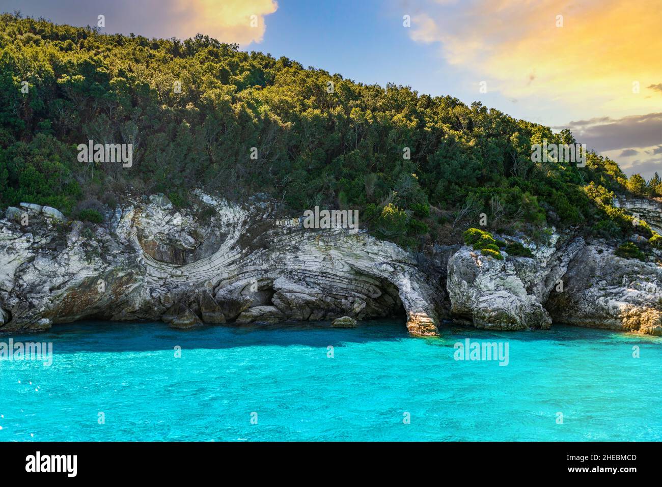 White layered rocks of high mountain covered with dense forest on top ...