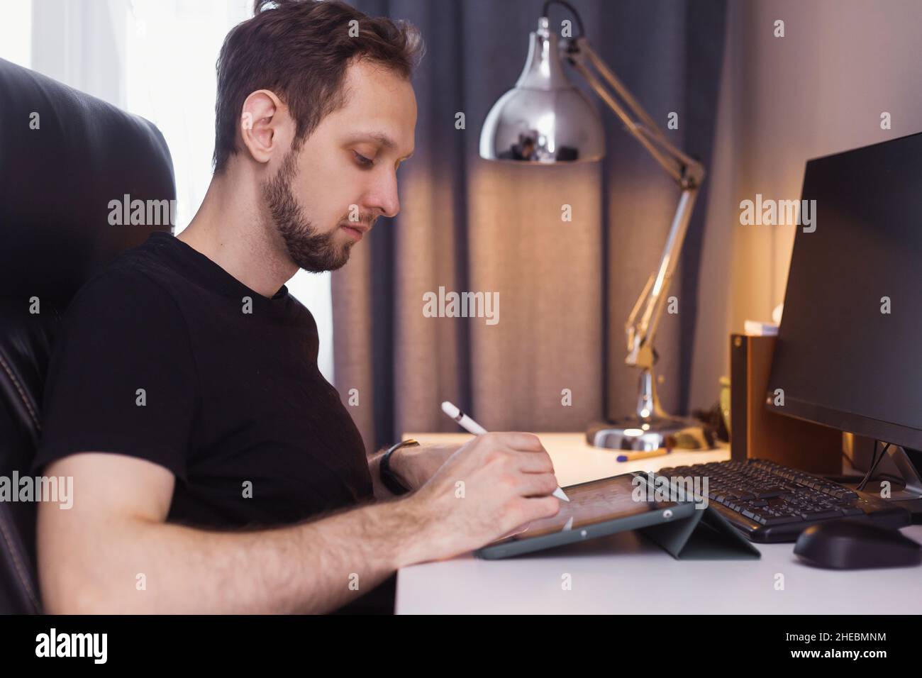Man using digital tablet, holding stylus pen, working on laptop ...