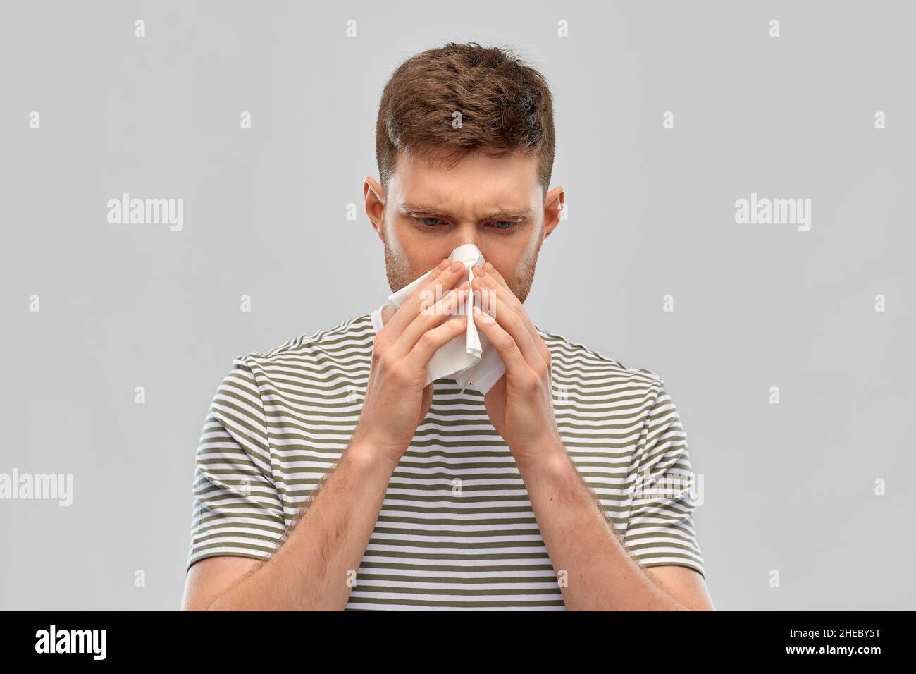 young man with paper tissue blowing his nose Stock Photo - Alamy
