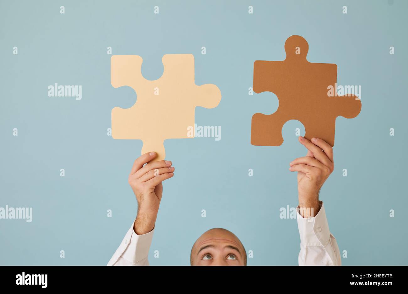 Man holding and joining brown and beige jigsaw puzzle pieces that match ...