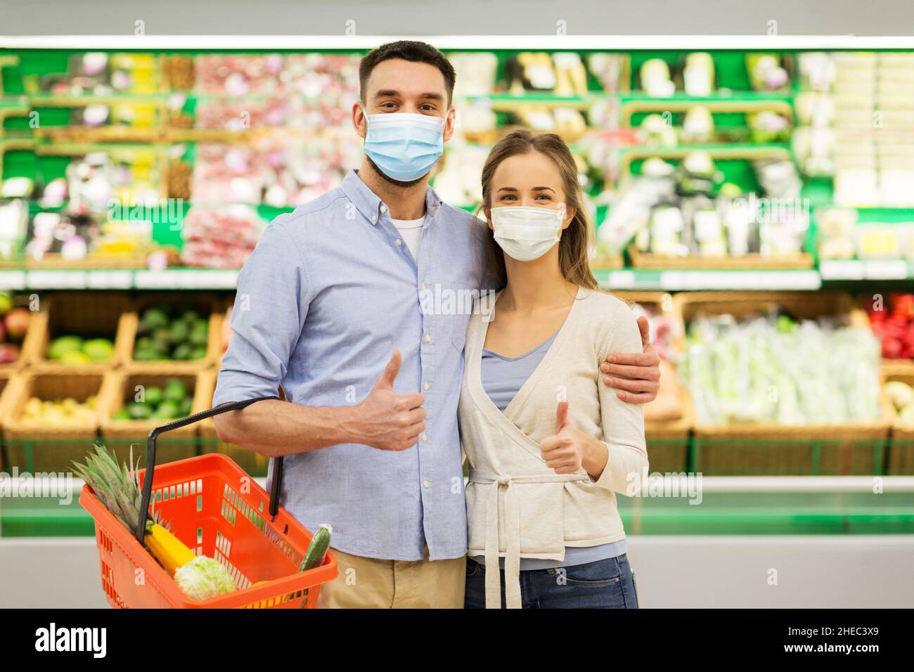 couple in masks with food basket at grocery store Stock Photo - Alamy