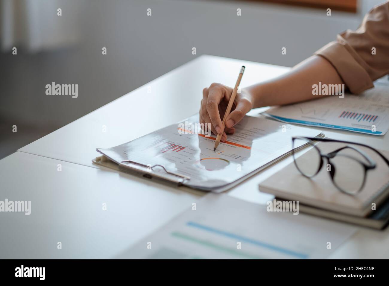 Close up hand of business woman analyst pointing with pencil paperwork ...