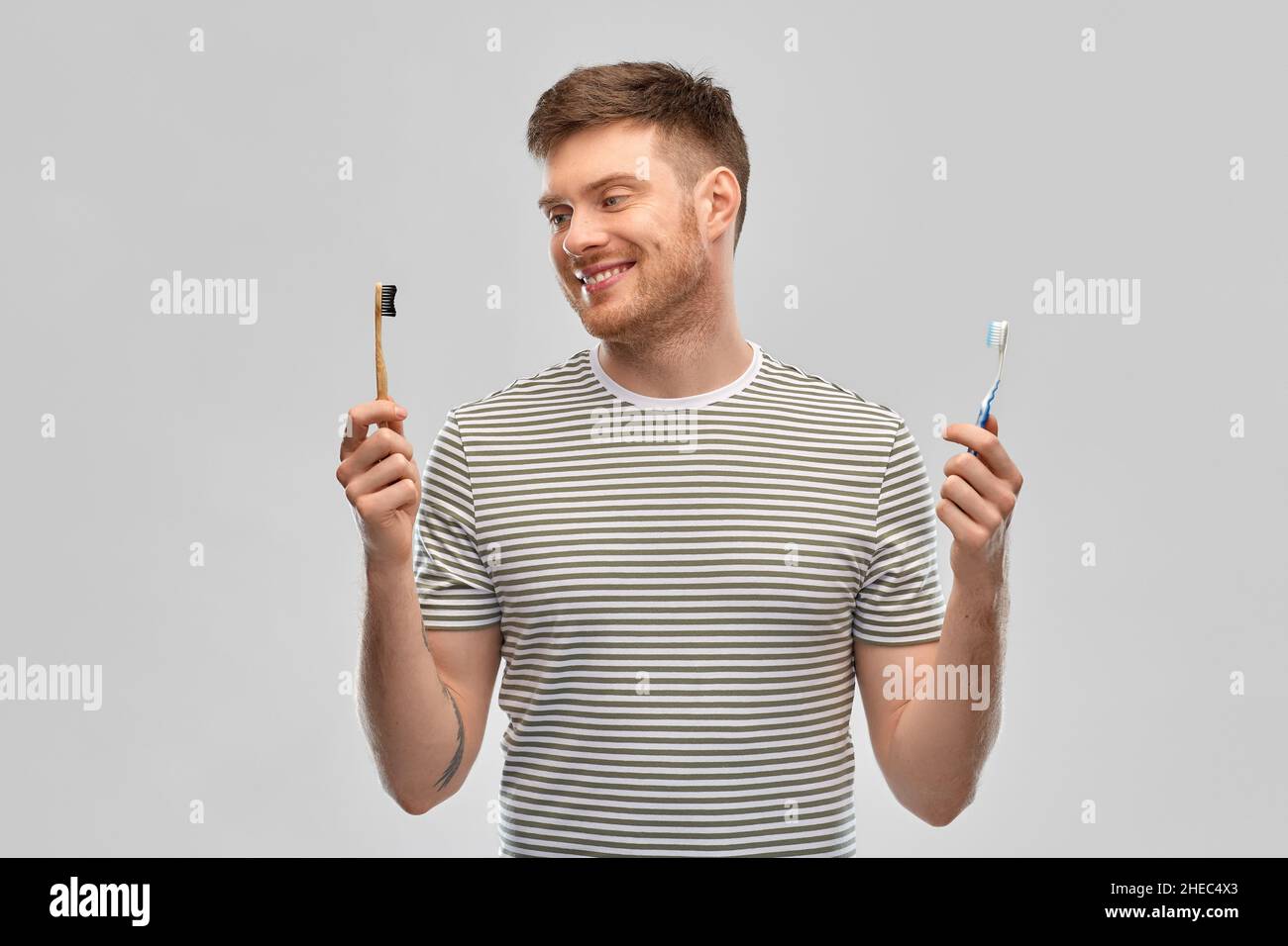 man comparing wooden and plastic toothbrush Stock Photo - Alamy