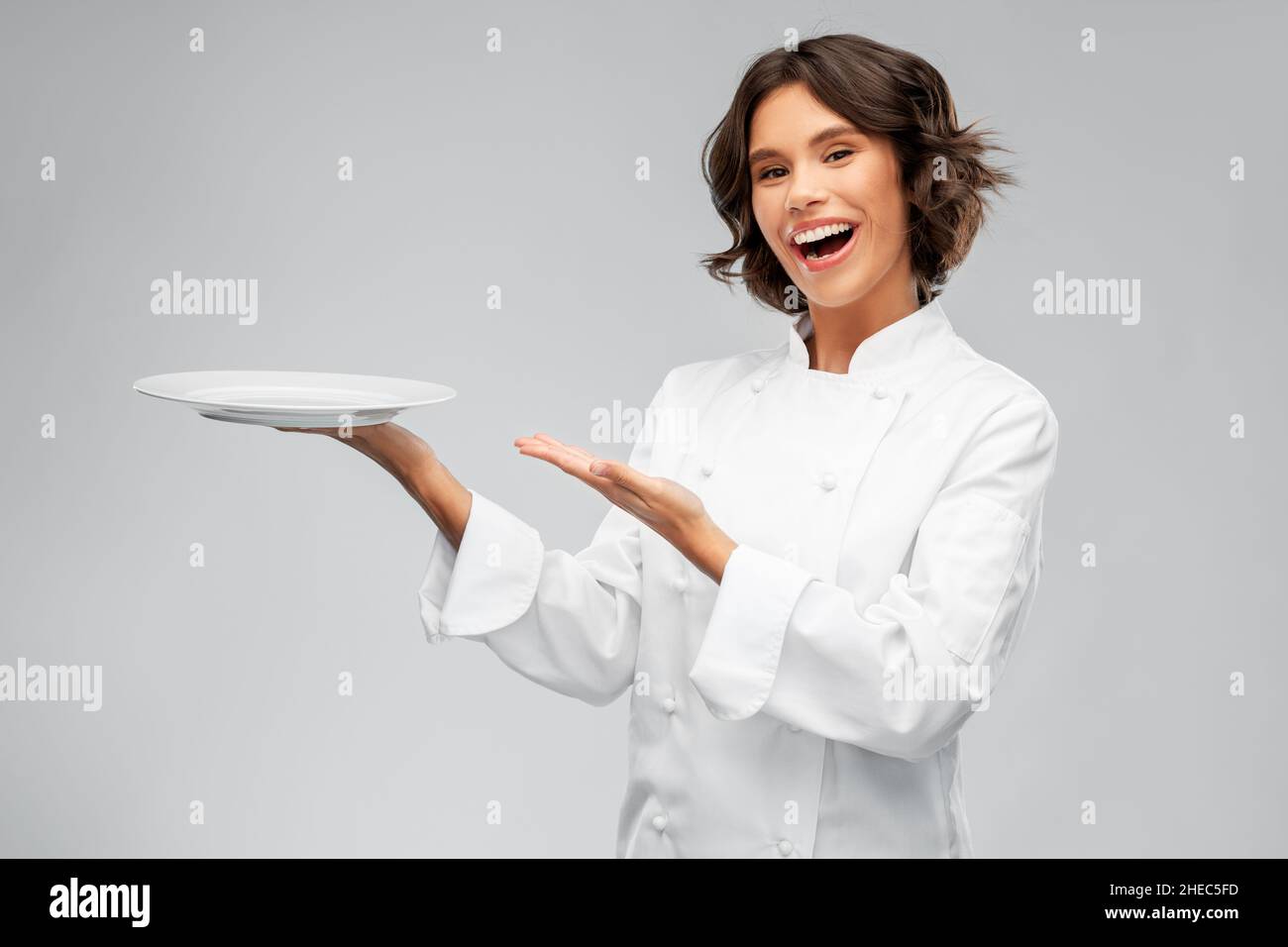 smiling female chef holding empty plate Stock Photo - Alamy