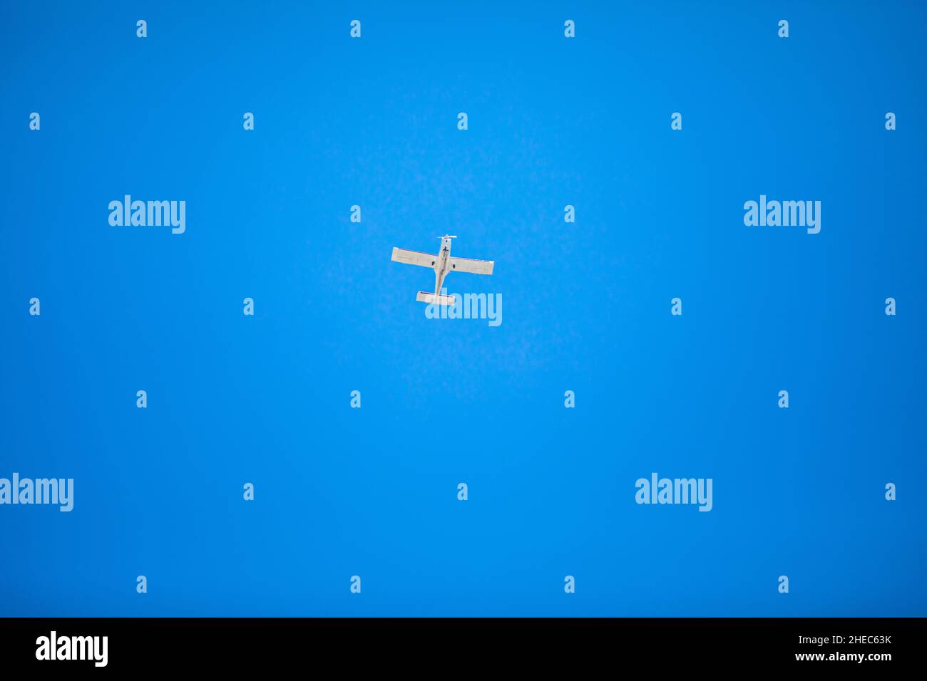 A small light plane flies in the clear sky. View from below. Horizontal ...