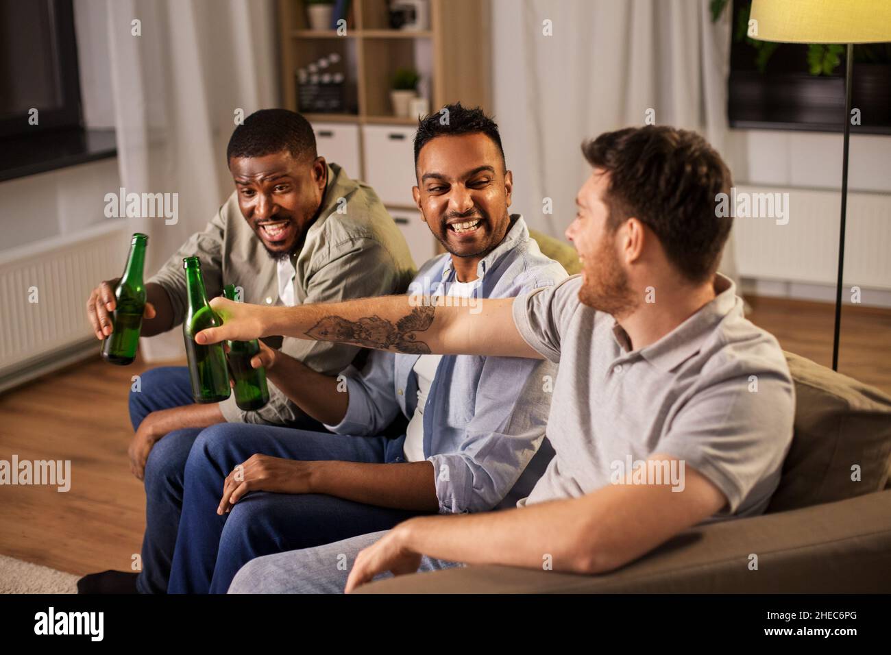 happy male friends drinking beer at home at night Stock Photo - Alamy