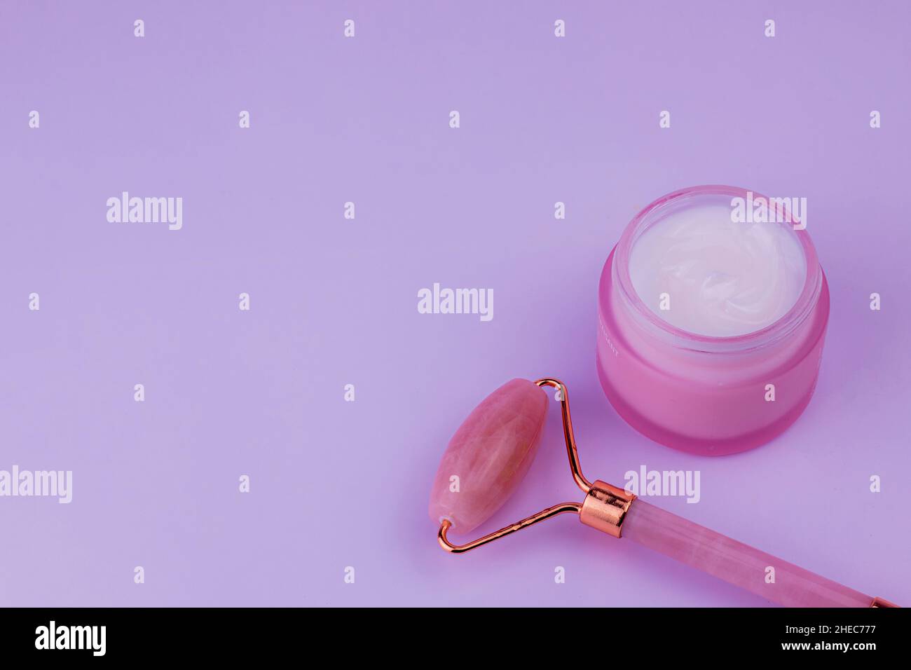 Facial massage roller and face cream on pink background. Cosmetic ...