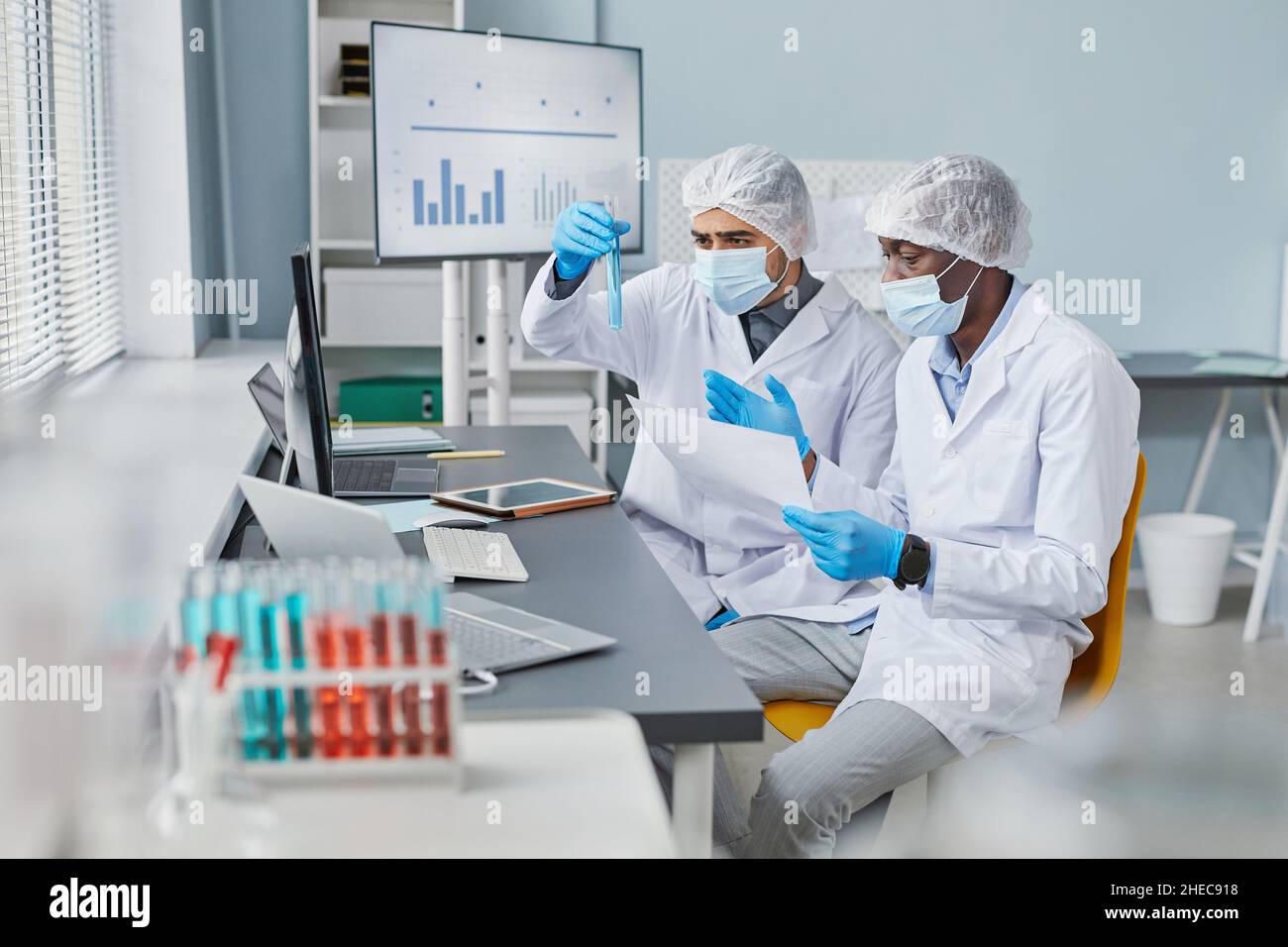 Two men in protective workwear sitting at the table and examining ...