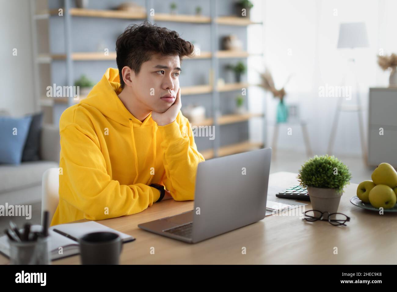Bored Asian male student sitting at desk with pc Stock Photo - Alamy