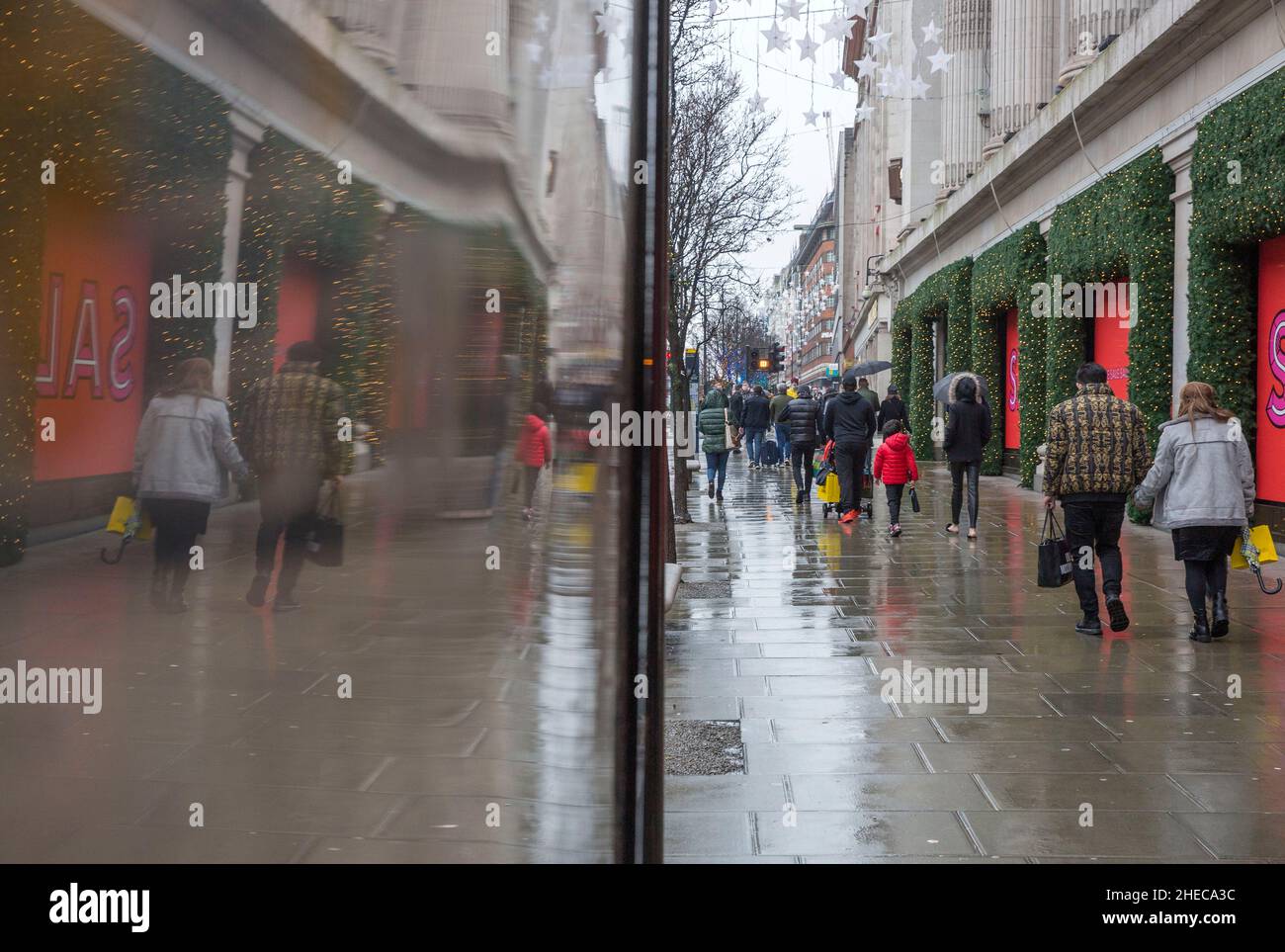 Shoppers are reflected in a bus stop wall as they walk on Boxing Day on ...