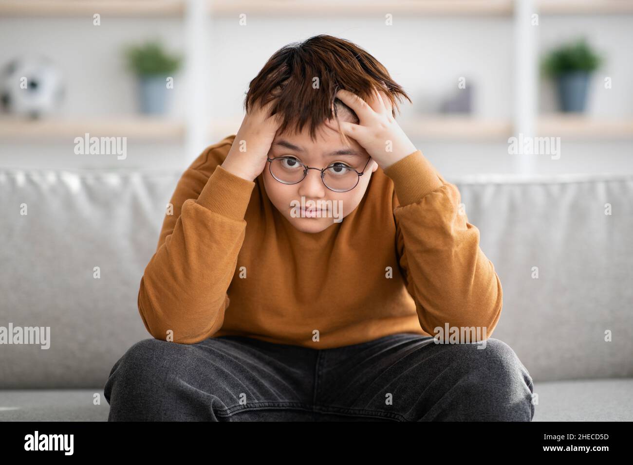 Stressed chinese boy looking at camera, home interior Stock Photo - Alamy