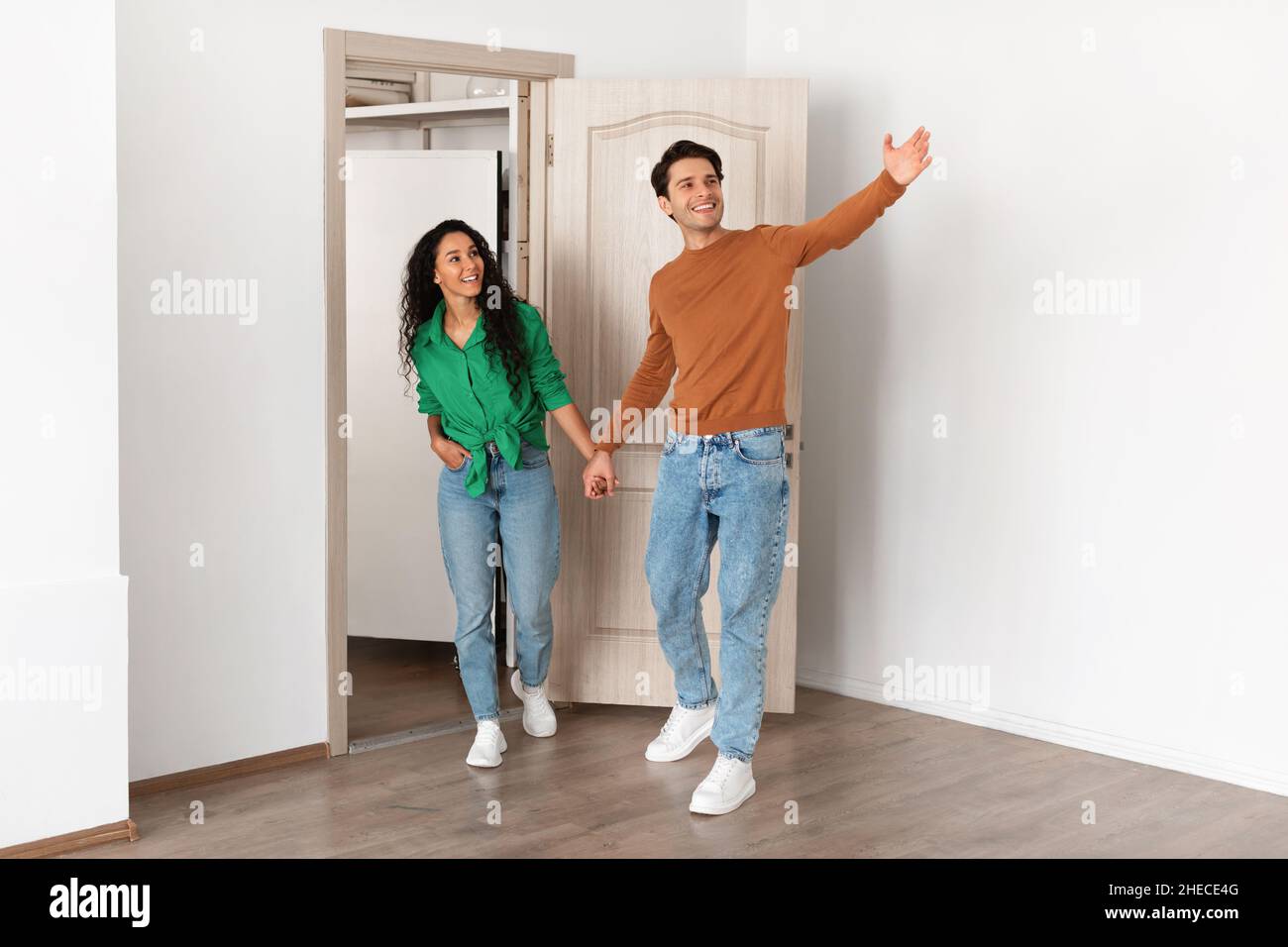 Happy guy inviting lady to enter home Stock Photo - Alamy