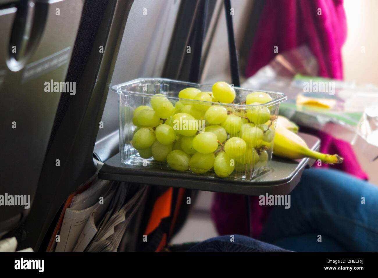 Healthy food, grapes and banana fruit, on a seat tray table, on an ...