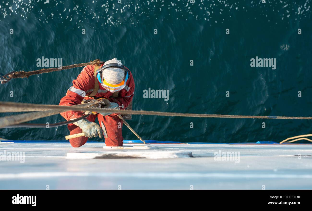 Seaman ship crew working aloft at height derusting and getting vessel ...