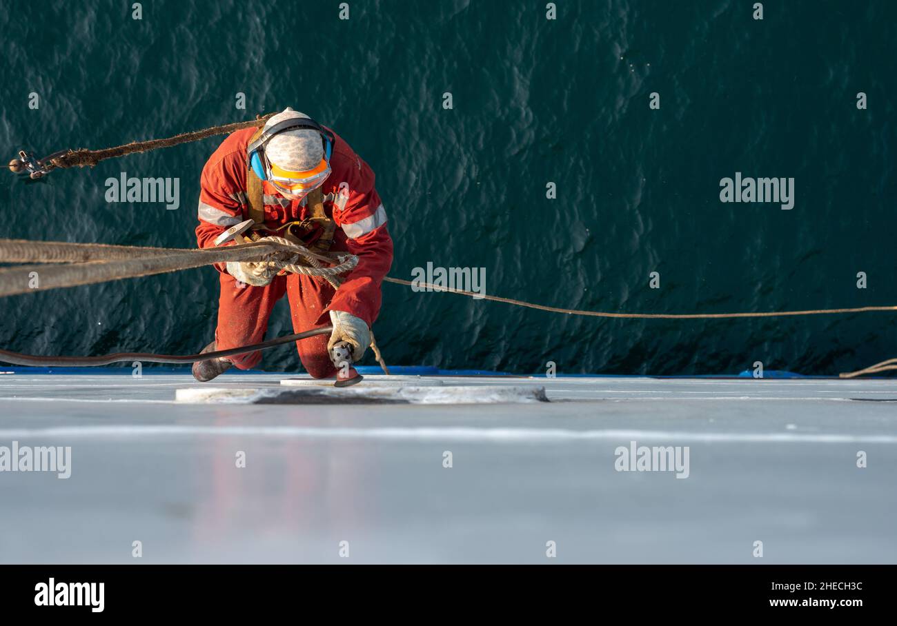 Seaman ship crew working aloft at height derusting and getting vessel ...