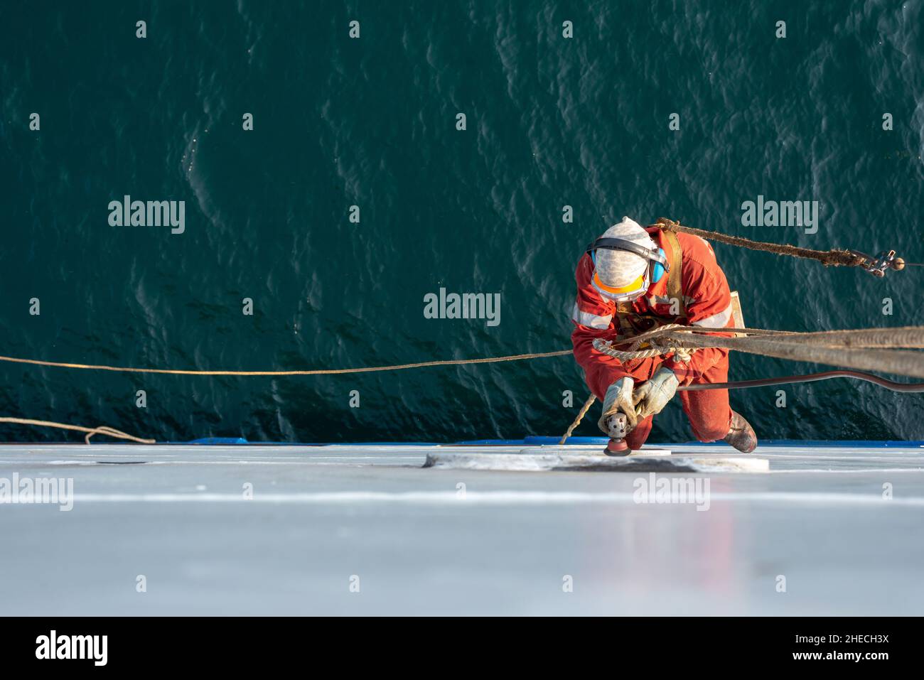 Seaman ship crew working aloft at height derusting and getting vessel ...