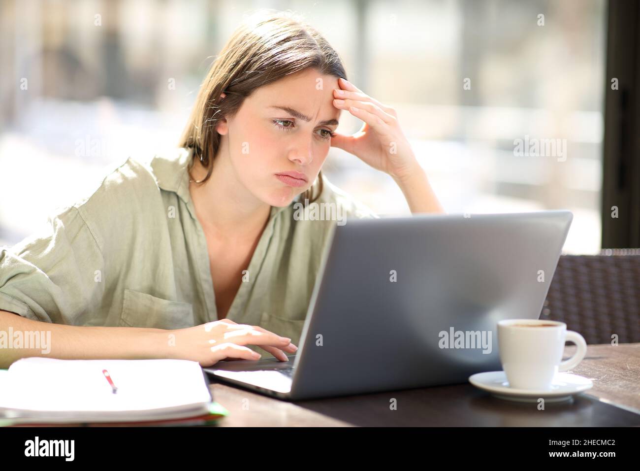 Frustrated student checking online content on laptop in a coffee shop ...