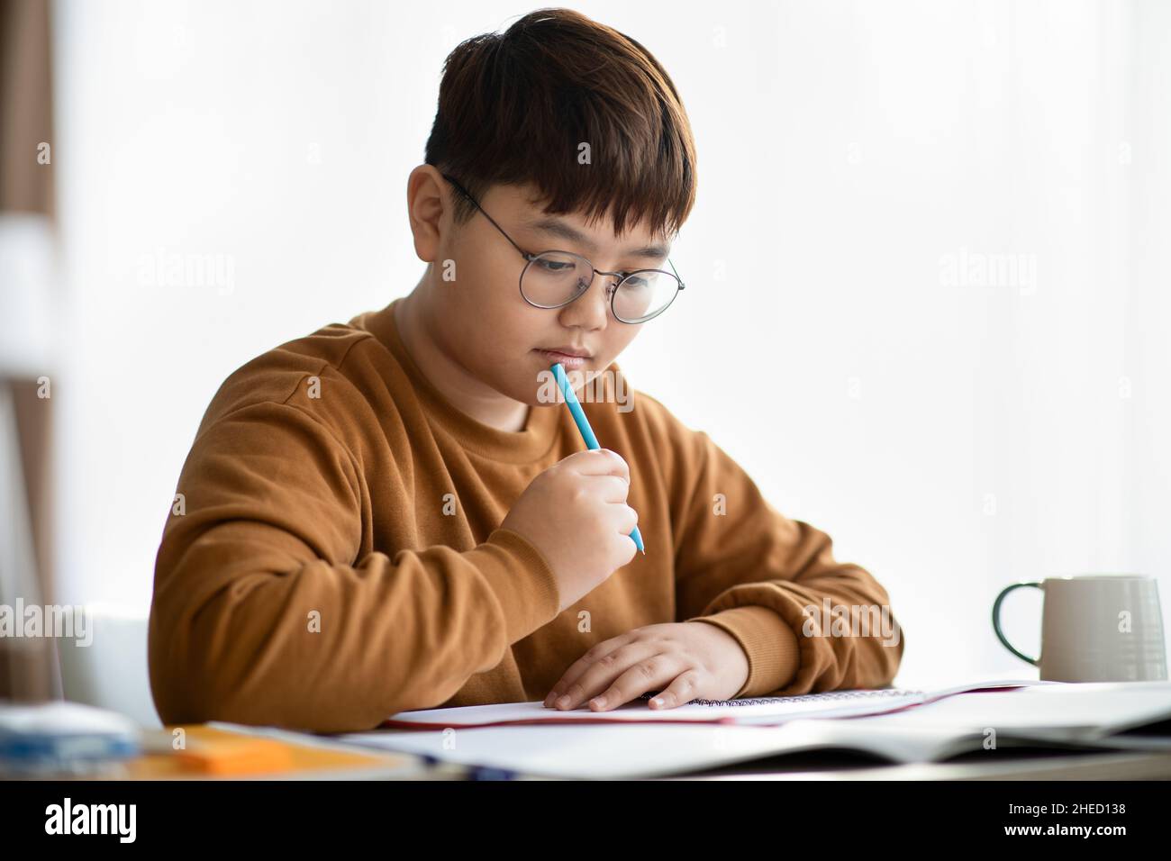 Concentrated chinese kid doing homework at home Stock Photo - Alamy