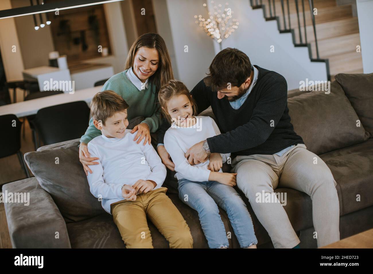Happy young family with two kids enjoy time together on couch in living ...